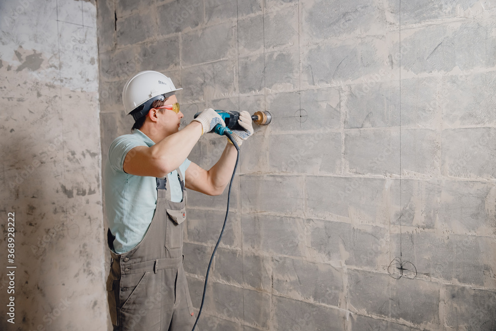 Builder worker pneumatic hammer drills hole in concrete brick wall with ...