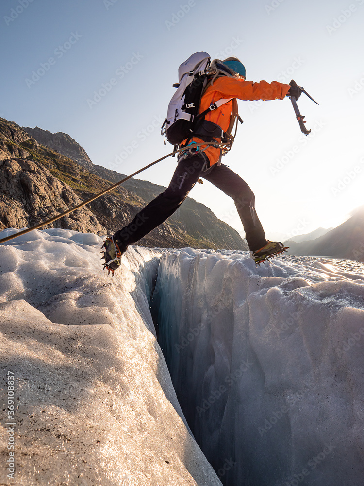 girl with ice axe jumping crevasse Stock Photo | Adobe Stock