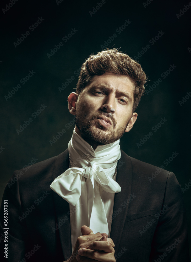 Sincere sin. Young man in suit as Dorian Gray isolated on dark green ...