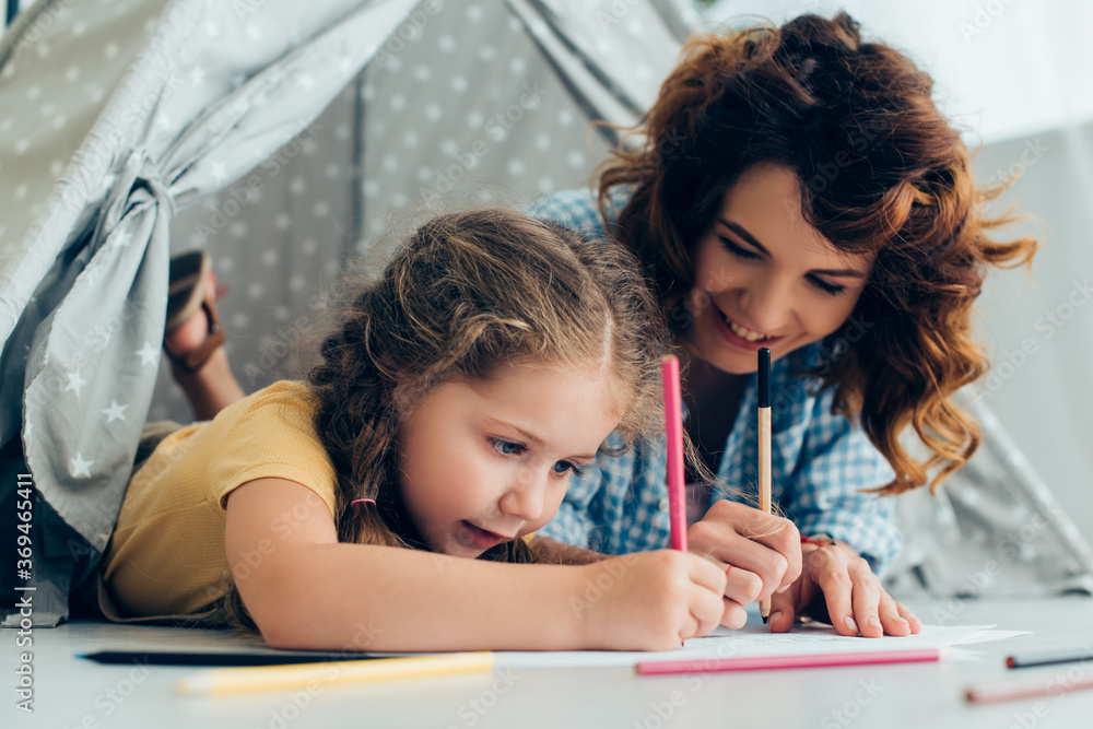 Happy babysitter and child drawing together in play tent Stock Photo ...