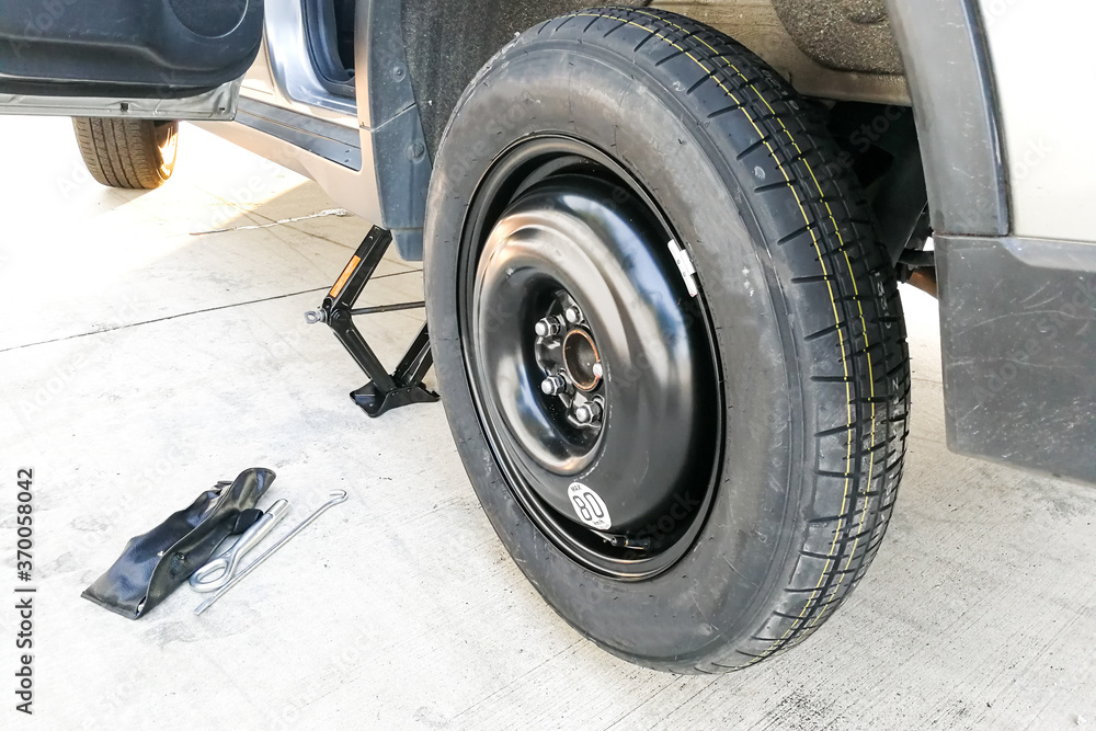 Temporary emergency tire replaced onto car wheel after flat tire Stock ...