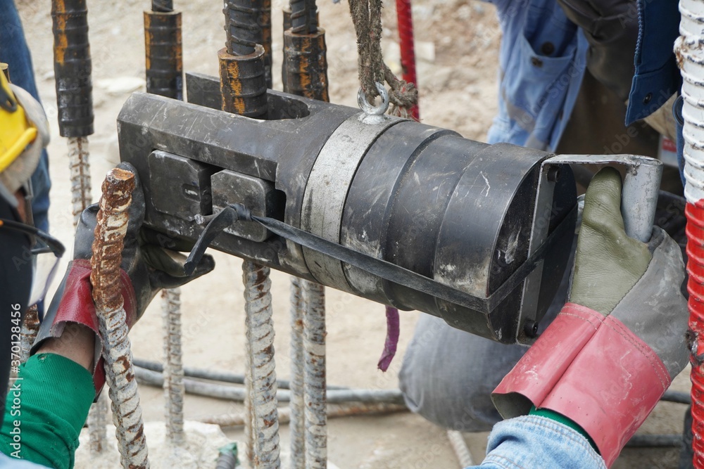 Worker is using a hydraulic press to squeeze the coupler to connect the ...