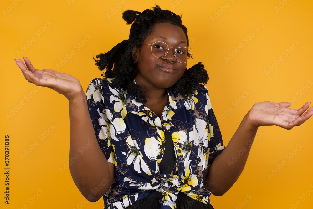 Puzzled and clueless young woman with arms out, shrugging her shoulders ...