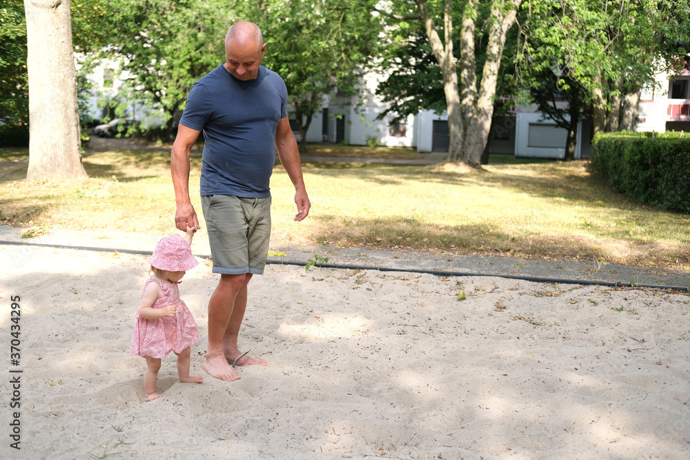 elderly bald man 60 years old leads a little girl, granddaughter, by ...