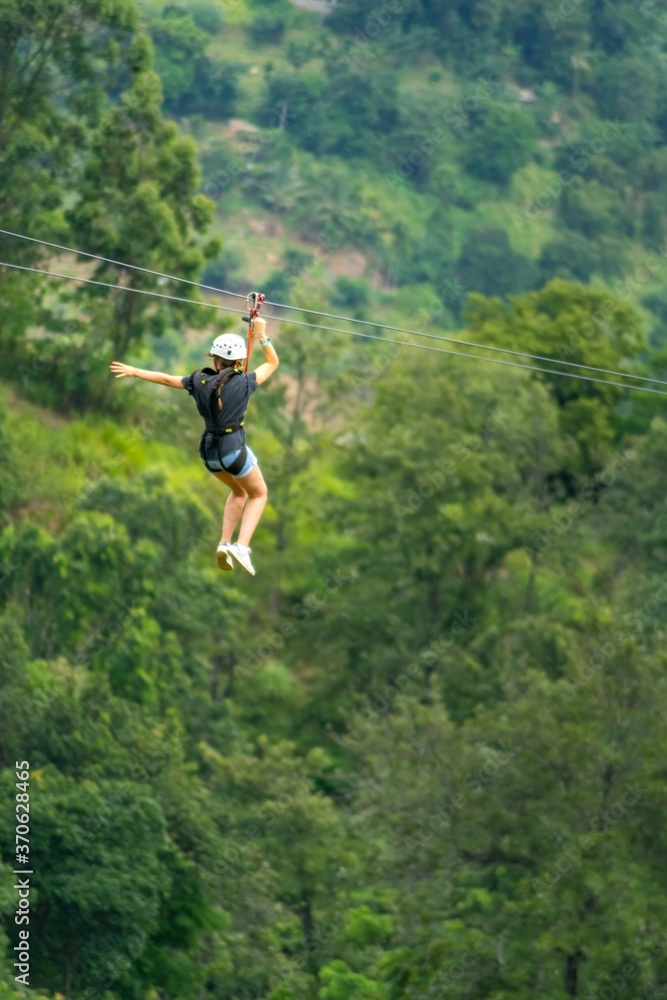 Young woman going on a zipline in the jungle. tree climbing in Sri ...