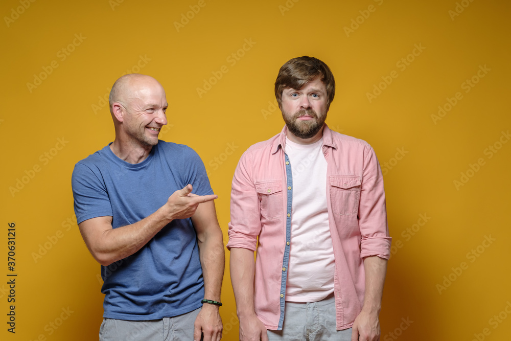 Foto de Stock Bald man taunts his upset, unhappy friend and mockingly ...