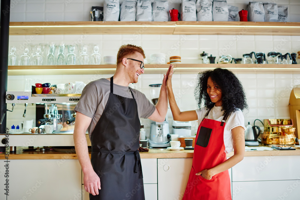 Positive caucasian male barista giving five to african american female ...
