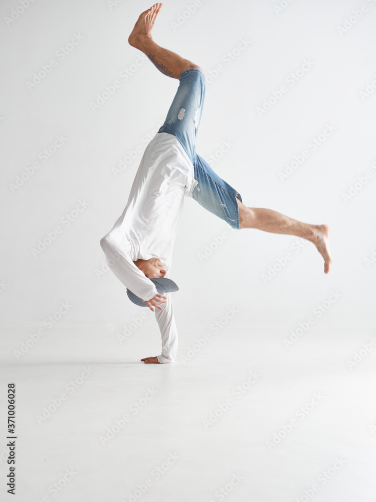 Young breakdancer stands on one hand upside down dancing hip-hop ...