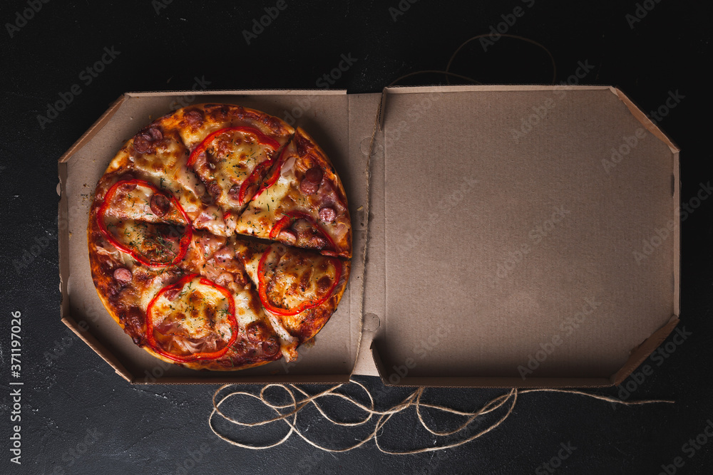 Italian pizza in a cardboard box on the black concrete background. Flat ...
