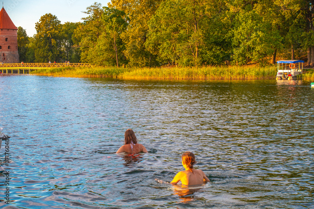 TRAKAI/LITHUANIA: 09/07/2019: Two young girls are swimming i in clear ...