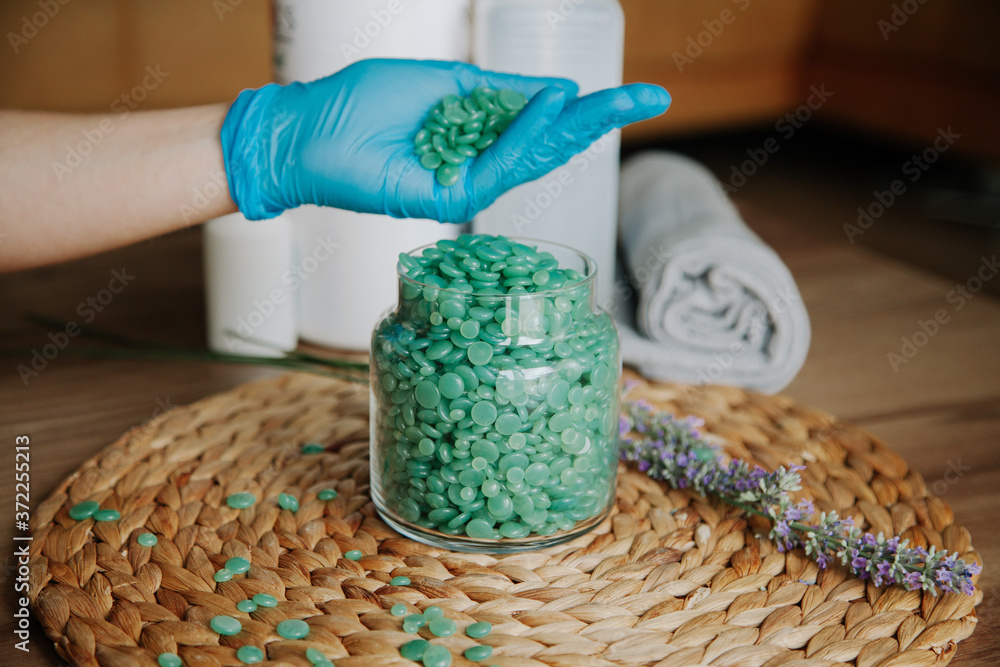 Epilation master holding Blue wax drops of sugaring paste in the ...
