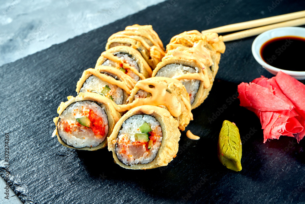 Deep fried sushi rolls with perch and cucumber in tempura on a black ...