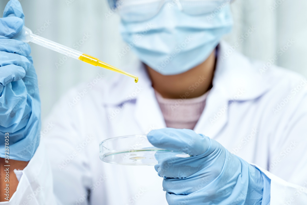 Doctor handhold the pipette and drop the yellow chemical liquid into a ...