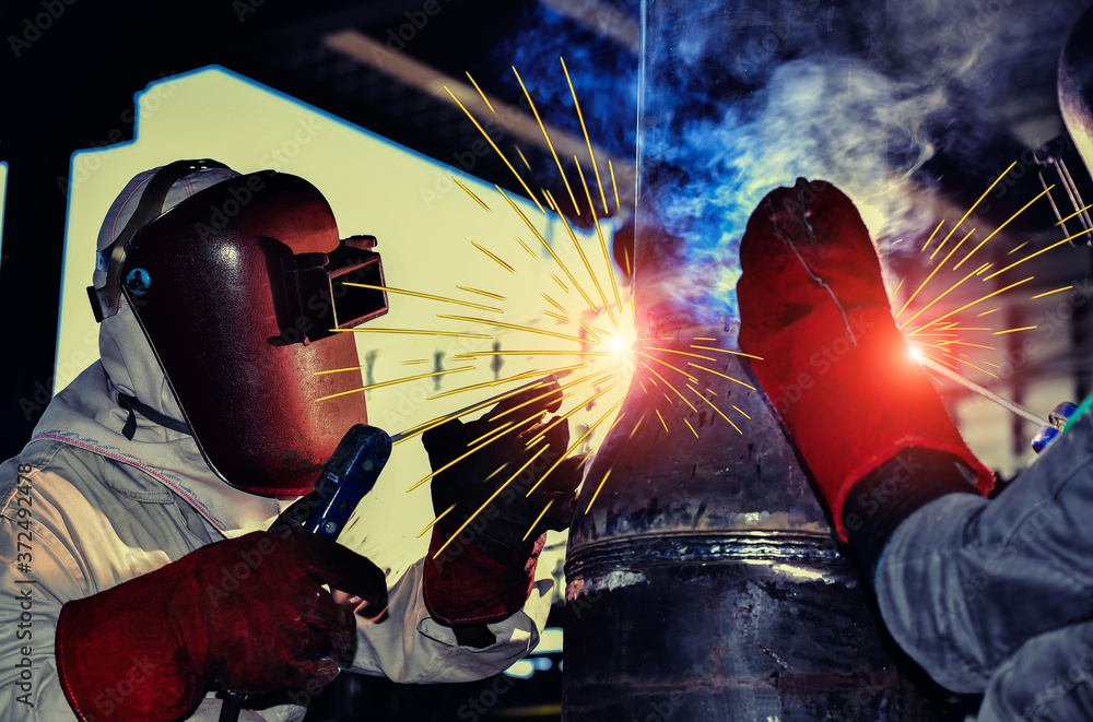 Welders Weldings Team on big steel pipe trench working hard to install ...