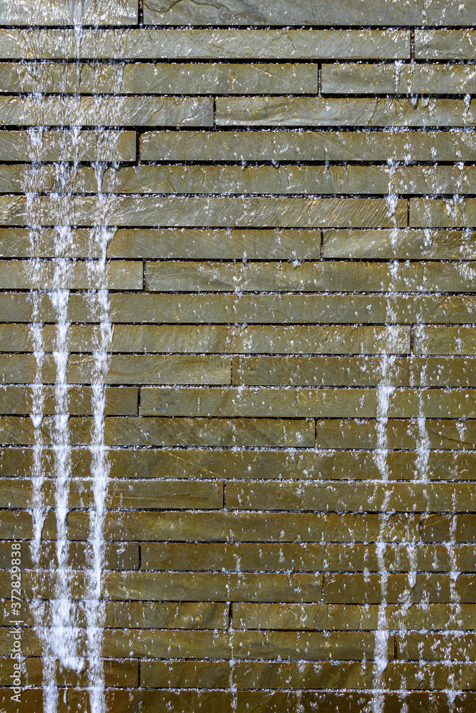 Water feature as a background, water running down a stone brick wall ...