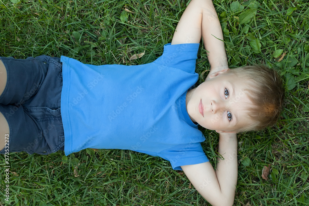 Pre-teen boy lying on back in grass, hands behind head, elevated view ...
