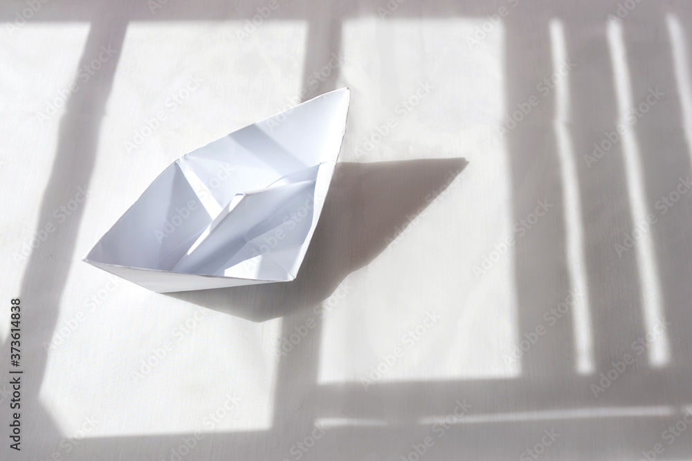 paper boat on shadows as waves of textile sea. White on white ...