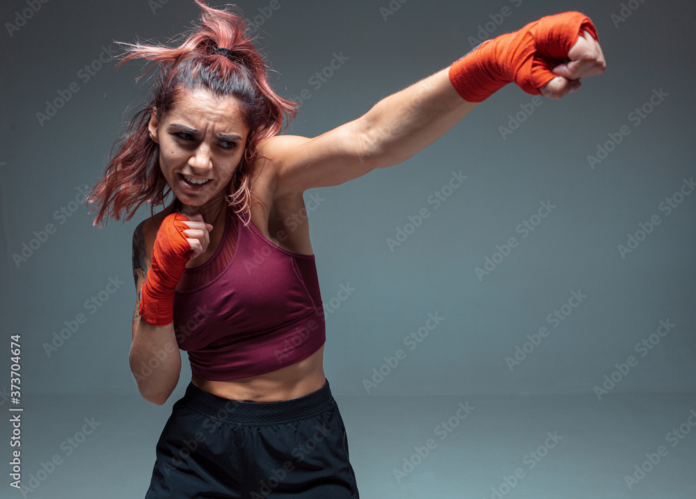 Beautiful female fighter boxing in studio isolated on gray background ...