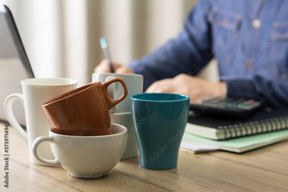 used coffee cups on the office desk and a man working hard drink ...