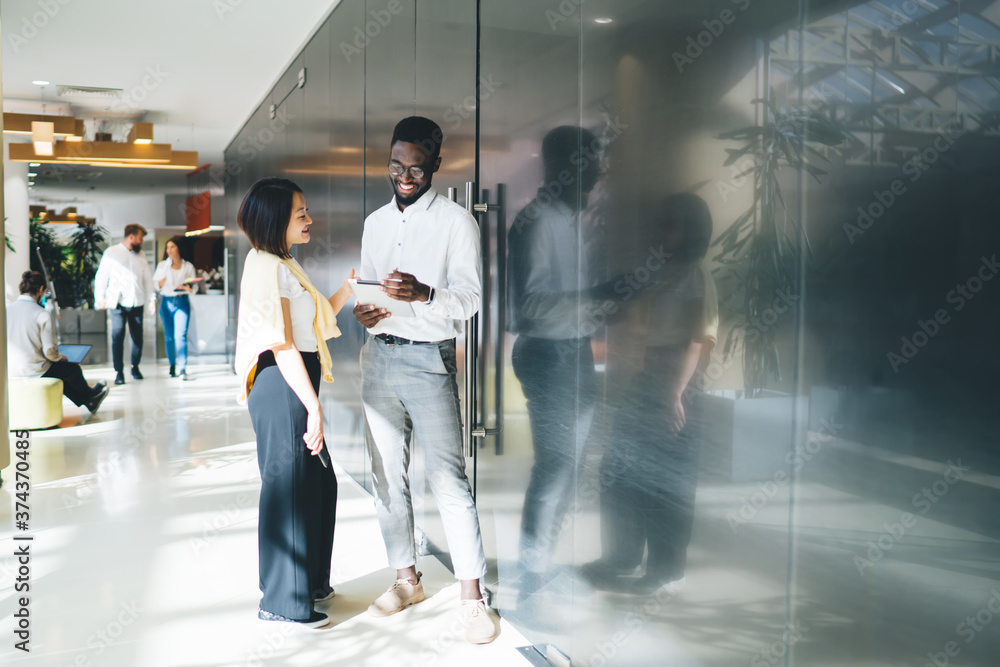 Diverse colleagues standing and moving in modern workplace talking over ...
