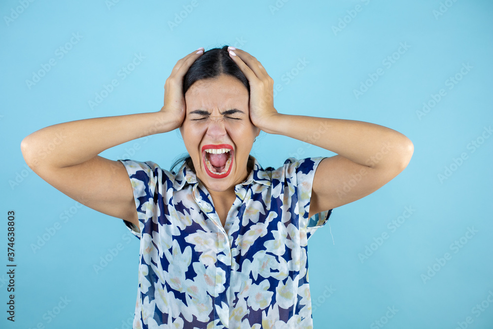 Young beautiful woman crazy and scared with hands on head, afraid and ...