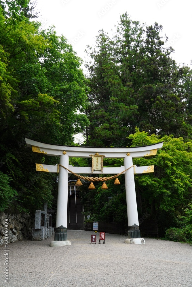 Shrine white and gold big gate called "Torii" . Japanese text on gate ...