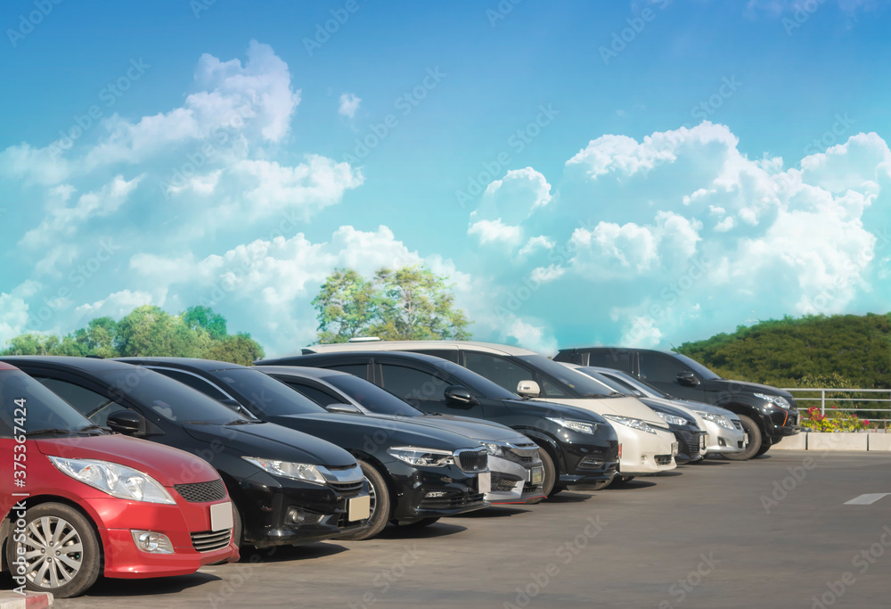 Car parked in large asphalt parking lot with white cloud and blue sky background. Outdoor ...