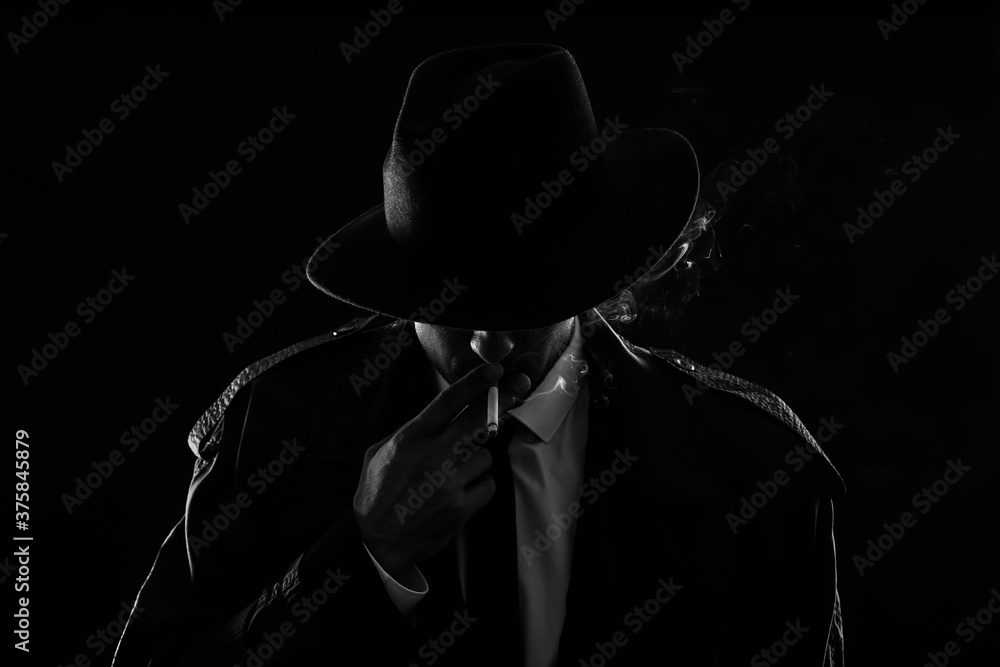 Old fashioned detective smoking cigarette on dark background, black and ...