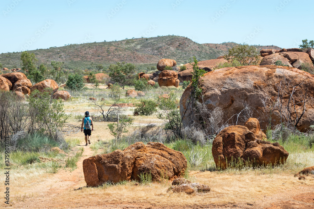 Male tourist walking across the Devils Marbles, sacred aboriginal place ...
