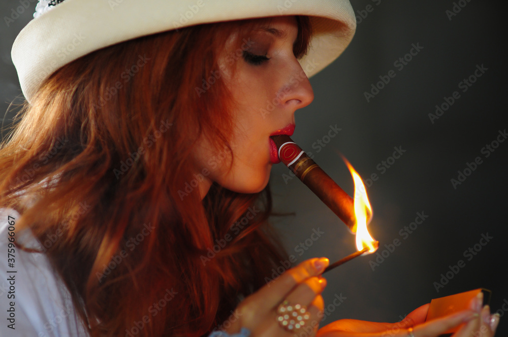 woman lit a match and lights a cigar.Elegant smoking woman. Portrait of ...