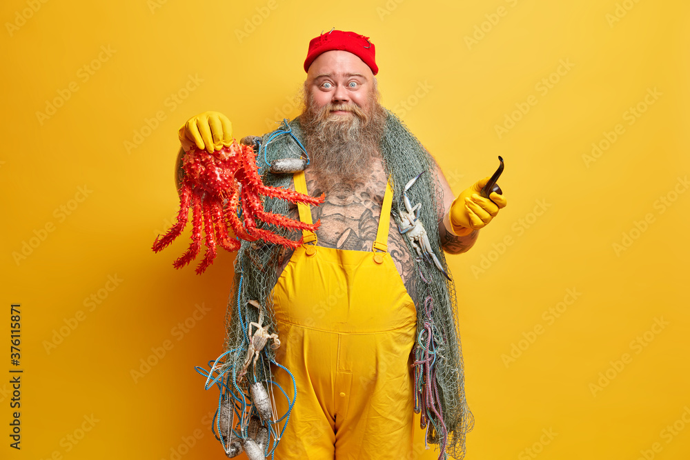Expressive cheerful bearded sailor man holds big octopus, carries ...