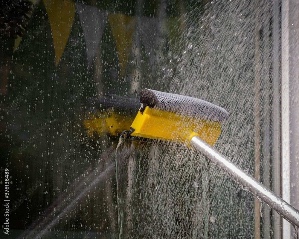woman cleaner wiping window glass with a telescopic MOP outside a ...