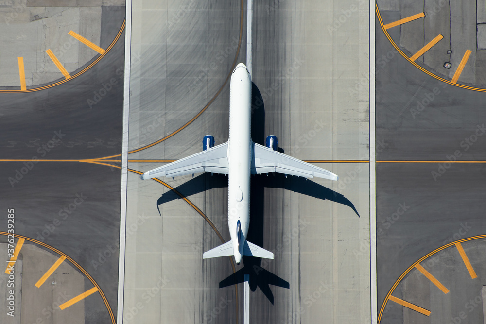 Aerial view of narrow body aircraft departing airport runway. Top down ...