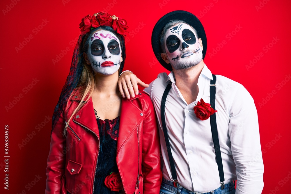 Couple wearing day of the dead costume over red looking sleepy and ...