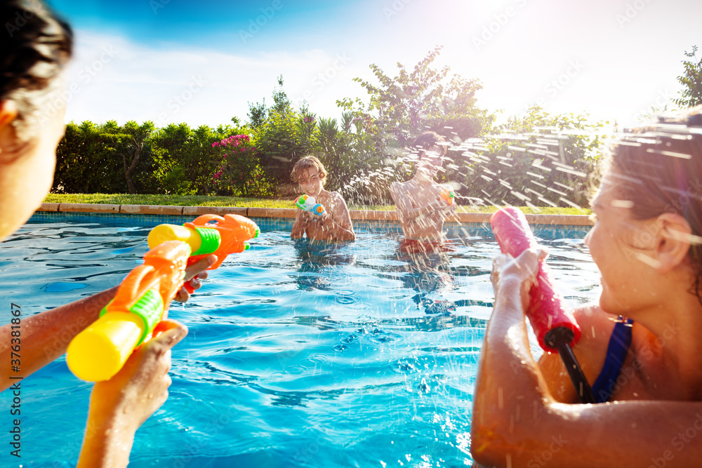 Group of kids in swimming pool shooting water-gun squirt pistol on ...