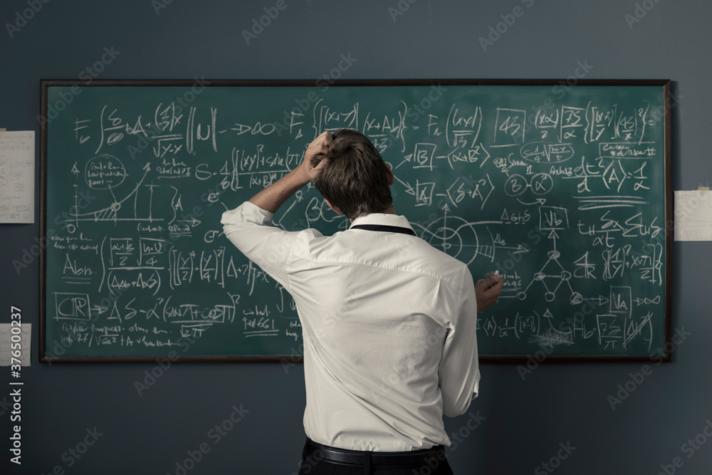 Mathematician solving problems and writing formulas on the chalkboard ...