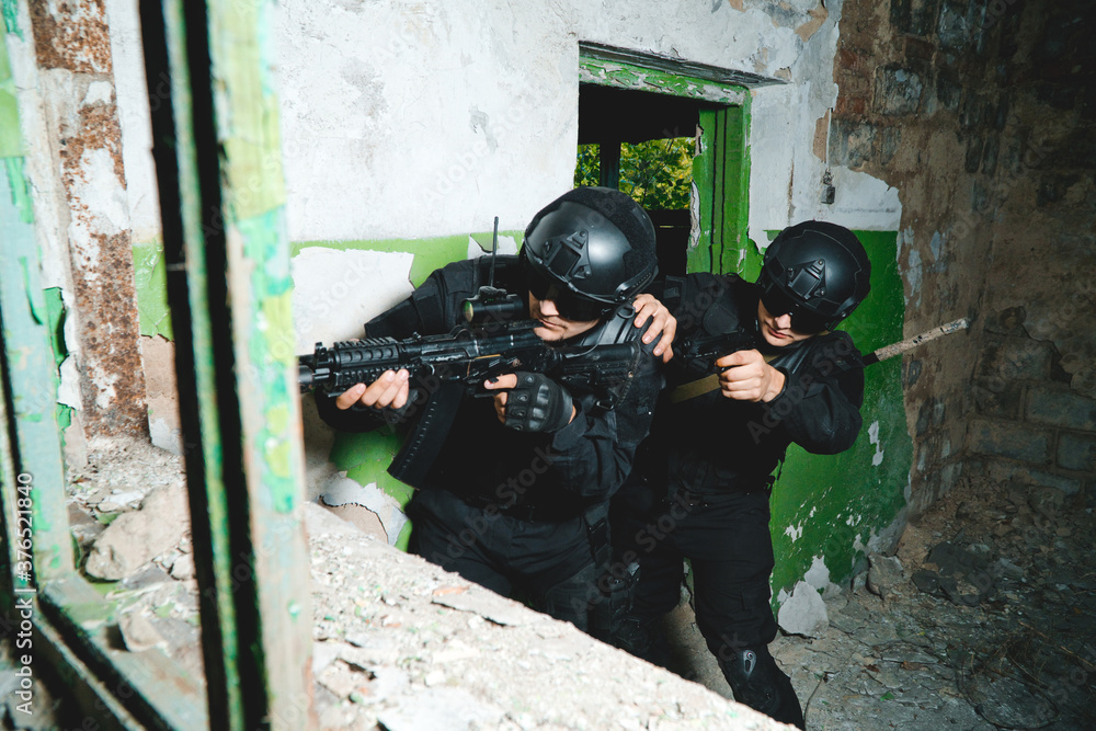 Two special forces soldiers covering each other and aiming with guns ...