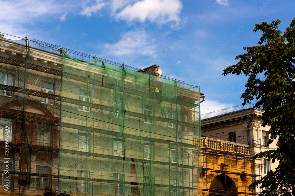 Facade renovation of old building in downtown with builders behind ...