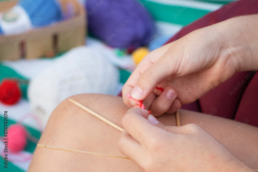 Hand weaving mandalas. A teacher on the beach shows her students how to ...