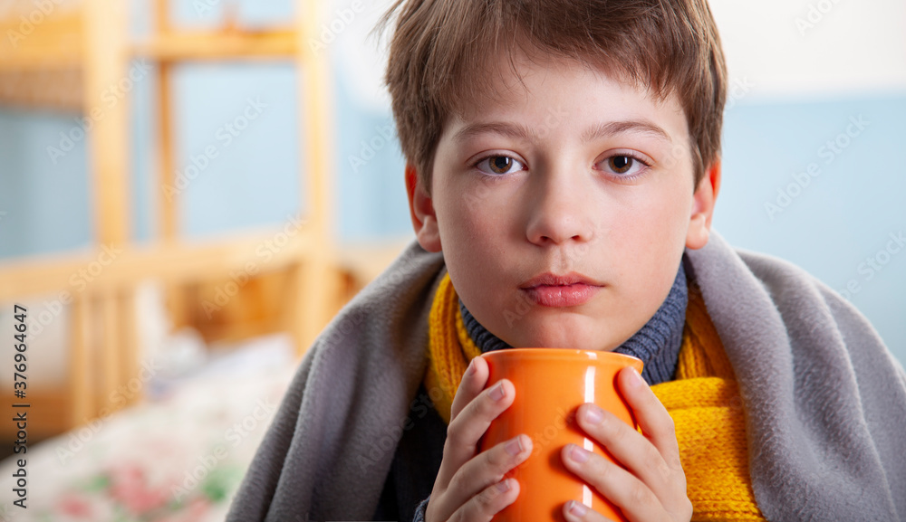 sick child boy drinking hot tea to recover from flu. sitting in bed a ...