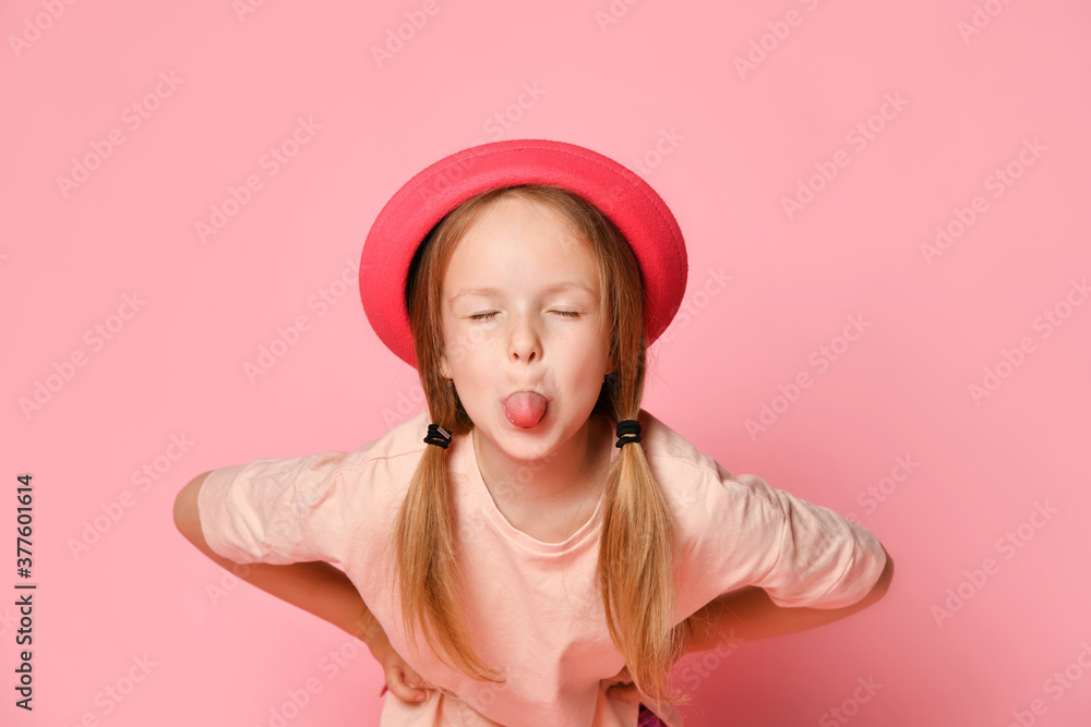 Mischievous little girl leaning forward with hands on hips and lolling ...