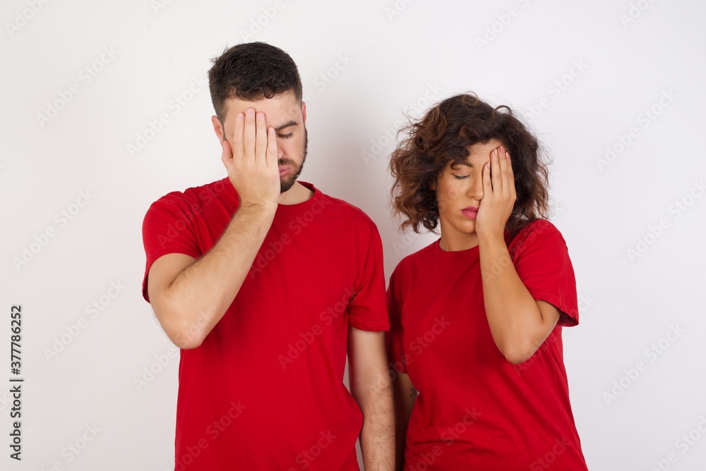 Tired overworked Young beautiful couple wearing red t-shirt on white ...