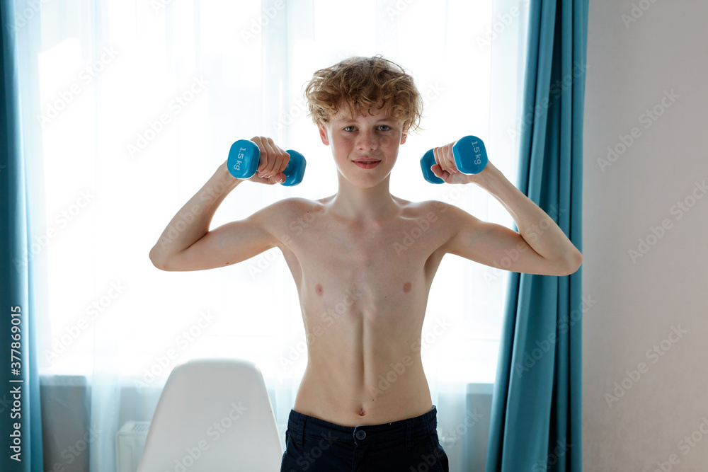 shirtless young caucasian strong teenager boy exercising at home, hold ...