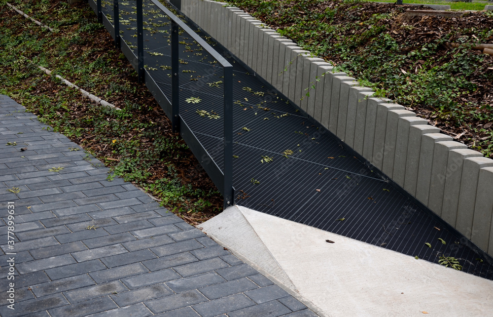 metal ramp for wheelchairs made of dark gray lattice and retaining wall ...