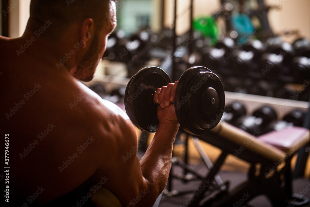 Fitness man lifting dumbbell. Man lifting dumbbell in a gym making ...