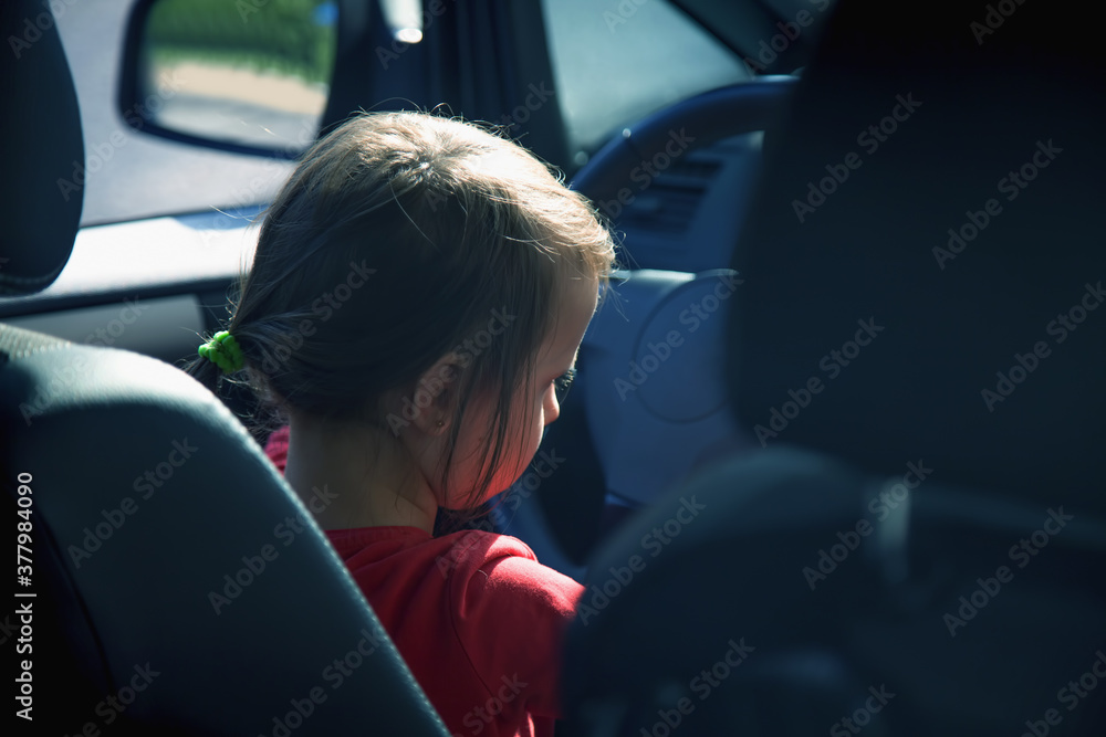 Dangers of underage driving. Back view of young girl in the car ...