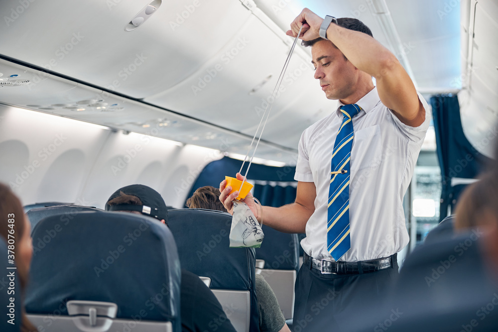 Man with oxygen mask demonstrating safety procedure prior to passenger ...