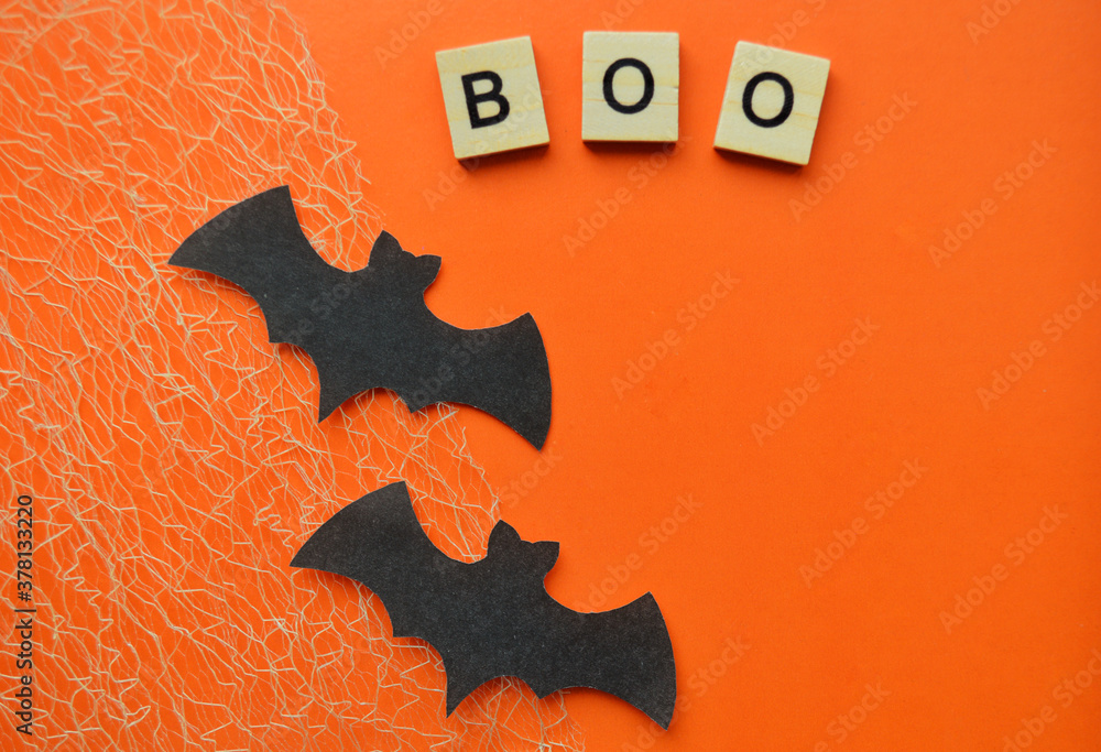Black paper bats lie on orange background with cobwebs. Word boo of ...