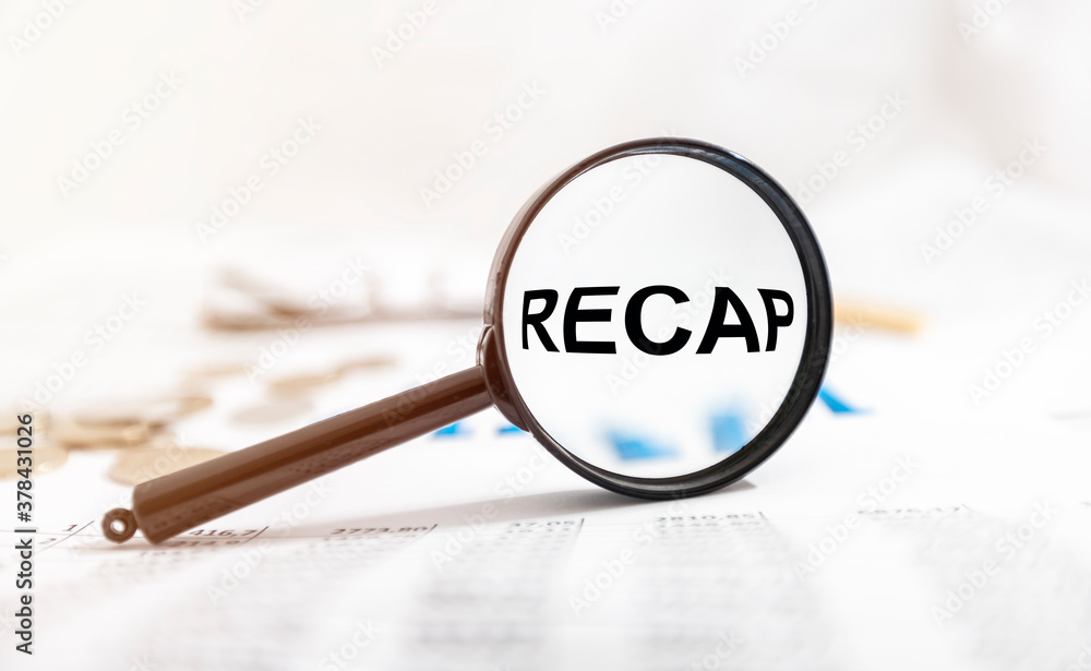 Recap word inscription through magnifying glass on white table with ...