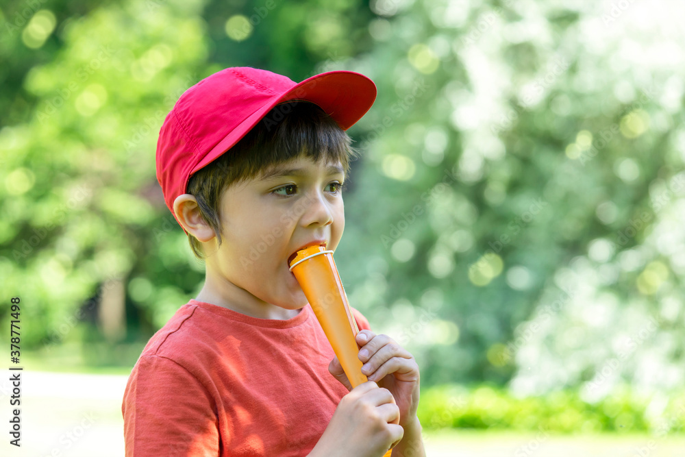 Portrait kid eating ice lolly with blurry nature background, Happy ...